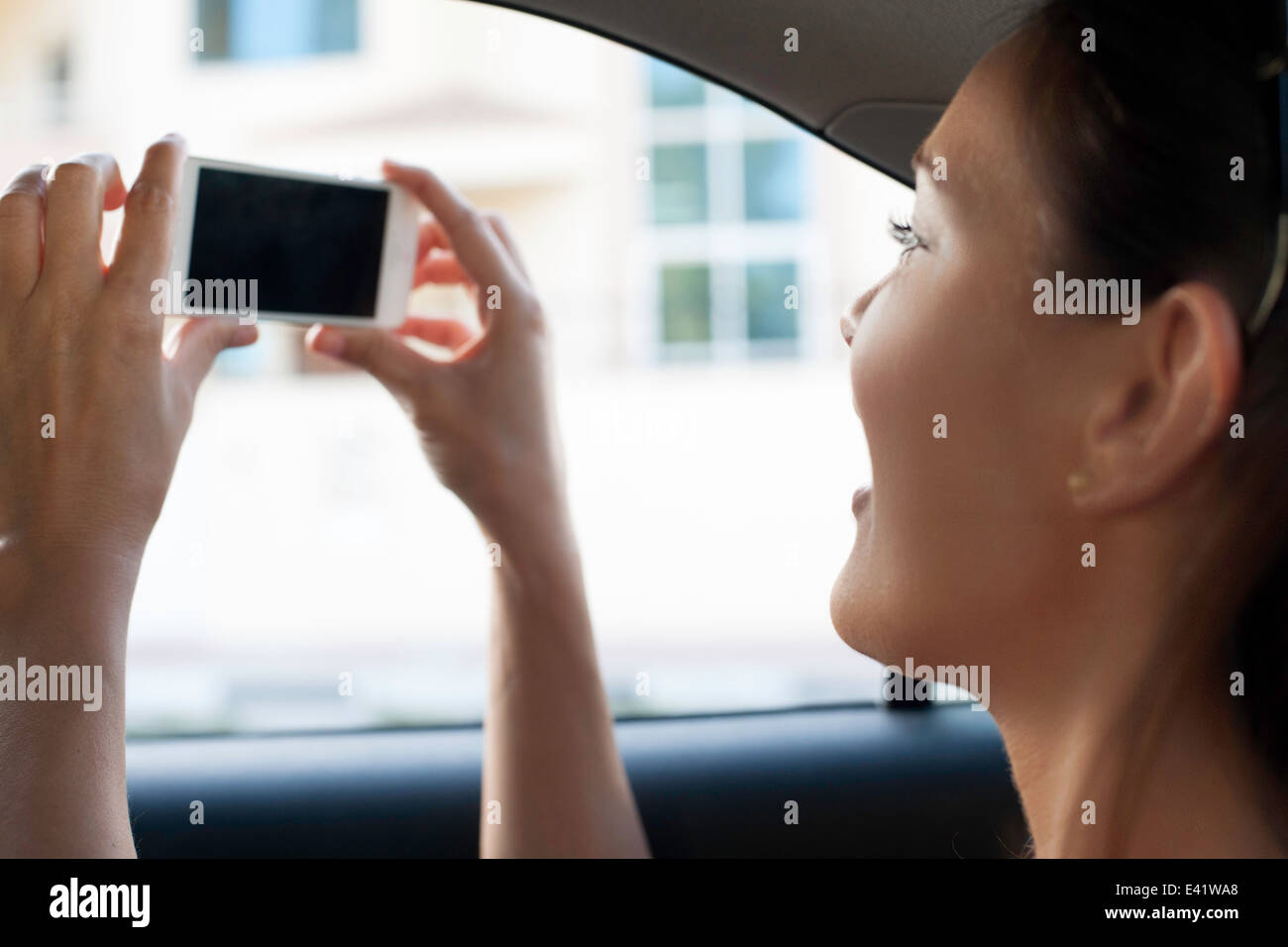 Close up of young woman photographing from taxi window Stock Photo - Alamy