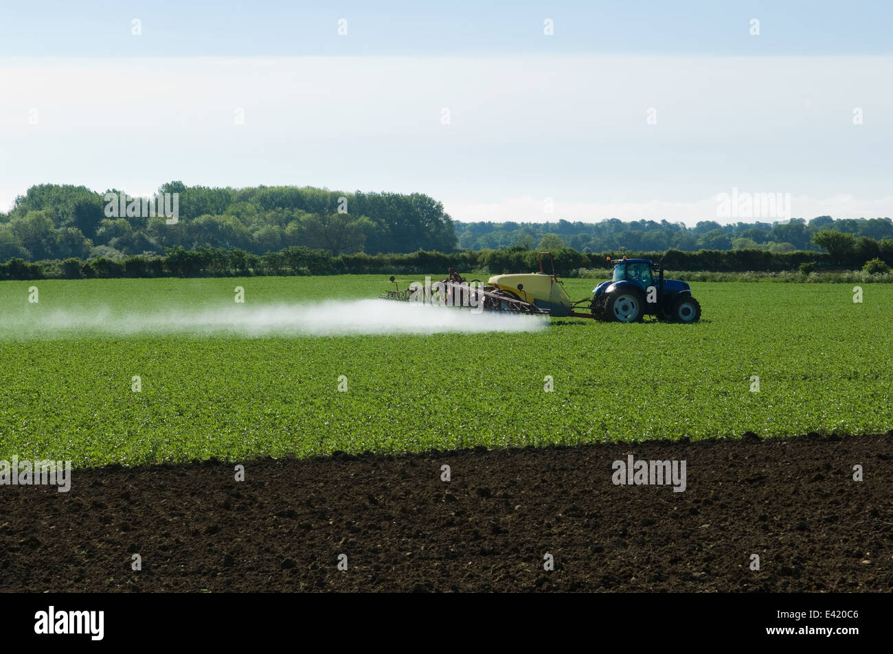 Tractor and crop sprayer spraying in field Stock Photo - Alamy