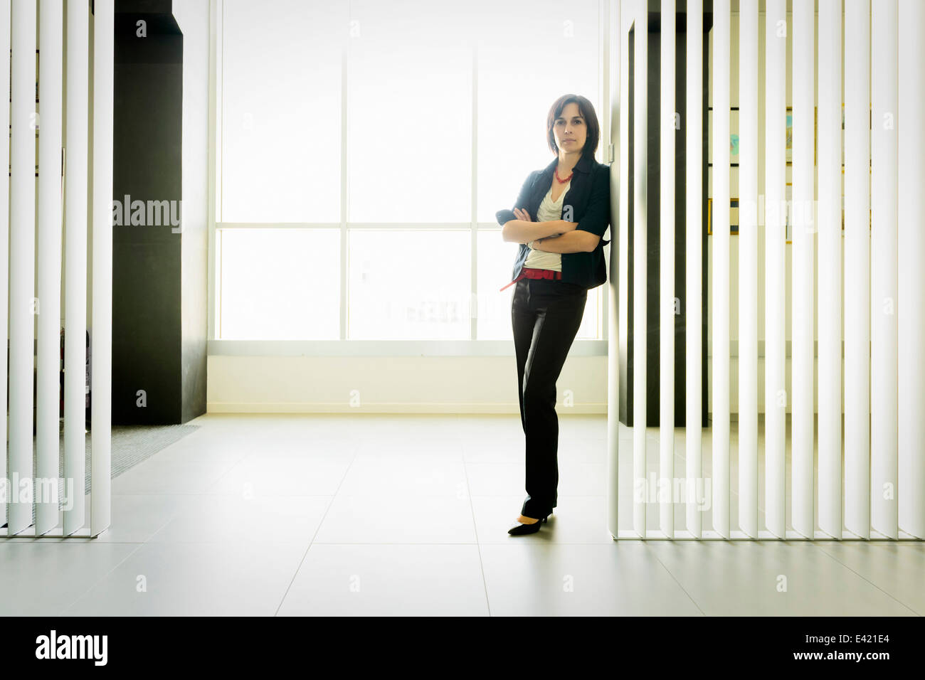 Businesswoman leaning against glass wall Stock Photo - Alamy