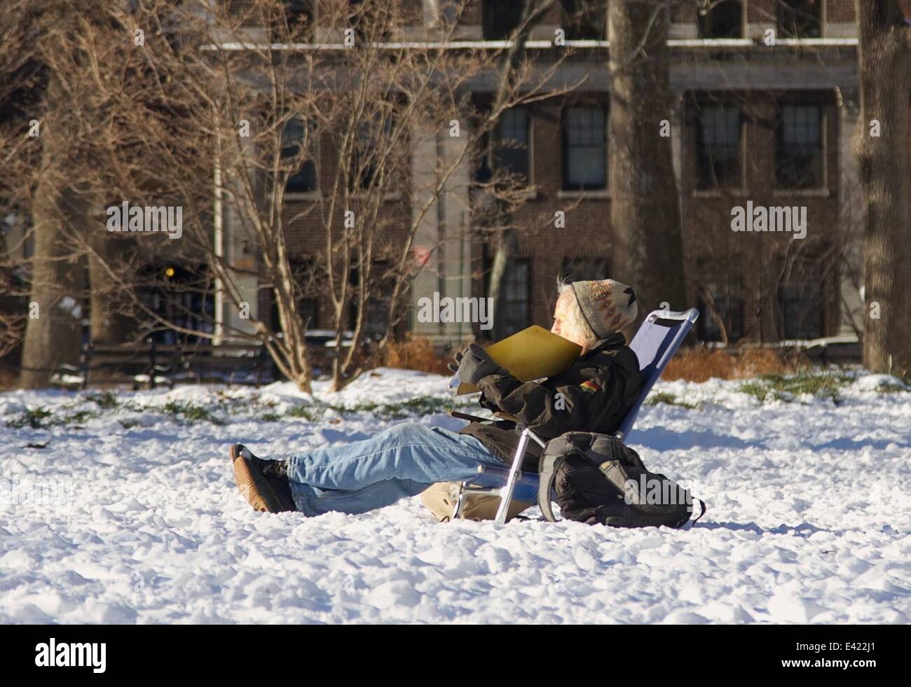 A man is snow tanning with a sun reflector on a lawn chair in ...
