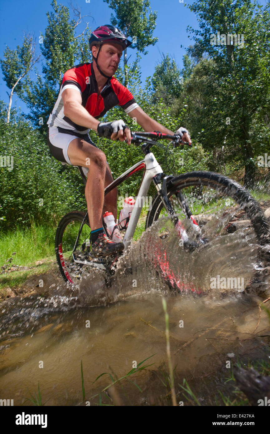 Male cyclist riding across stream Stock Photo - Alamy