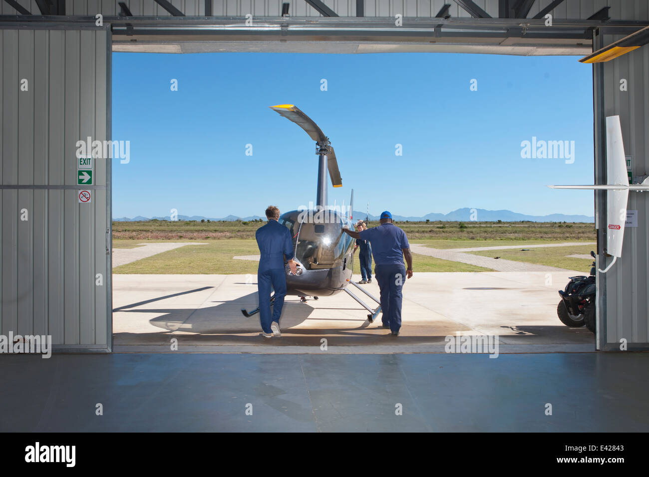 Pilots pushing helicopter onto tarmac Stock Photo - Alamy