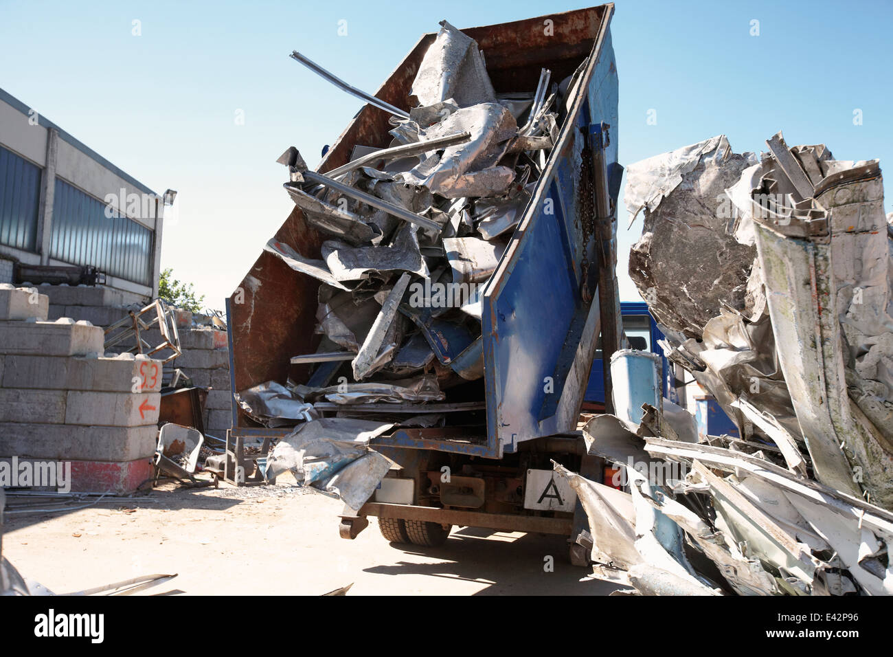 Dump truck emptying aluminium from skip into scrap yard Stock Photo - Alamy