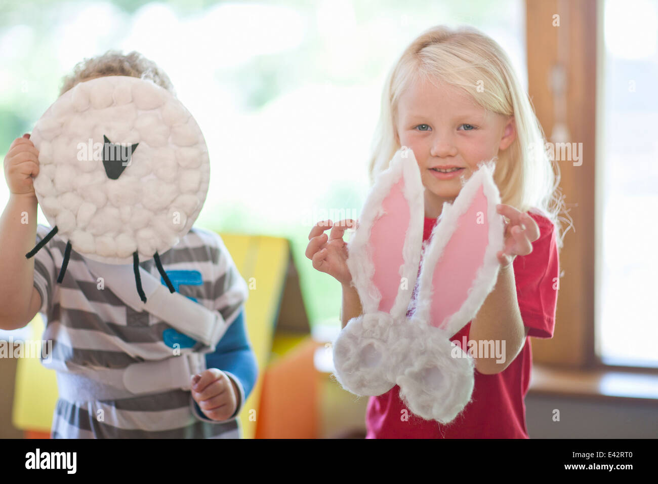 Boy and girl holding up sheep and rabbit creations at nursery school ...
