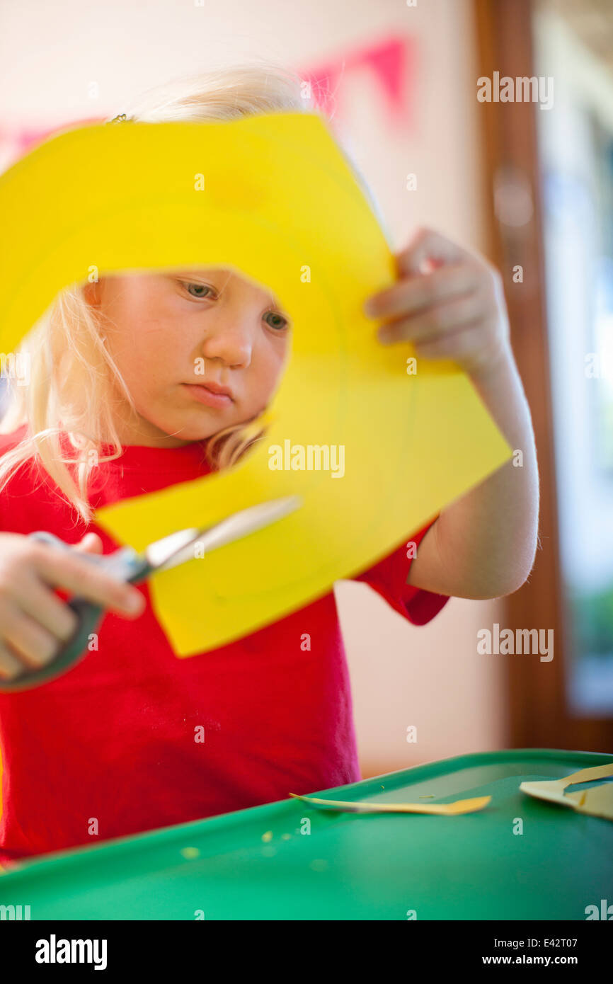 Girl cutting out cardboard shapes at nursery school Stock Photo - Alamy