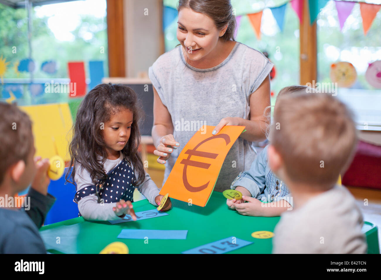 Teacher and pupils counting euro currency at nursery school Stock Photo ...