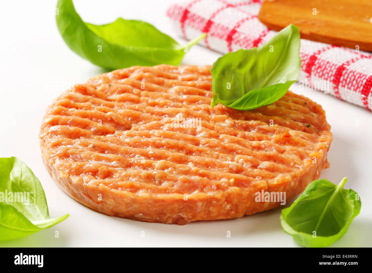 Raw burger patty with fresh basil leaves Stock Photo - Alamy