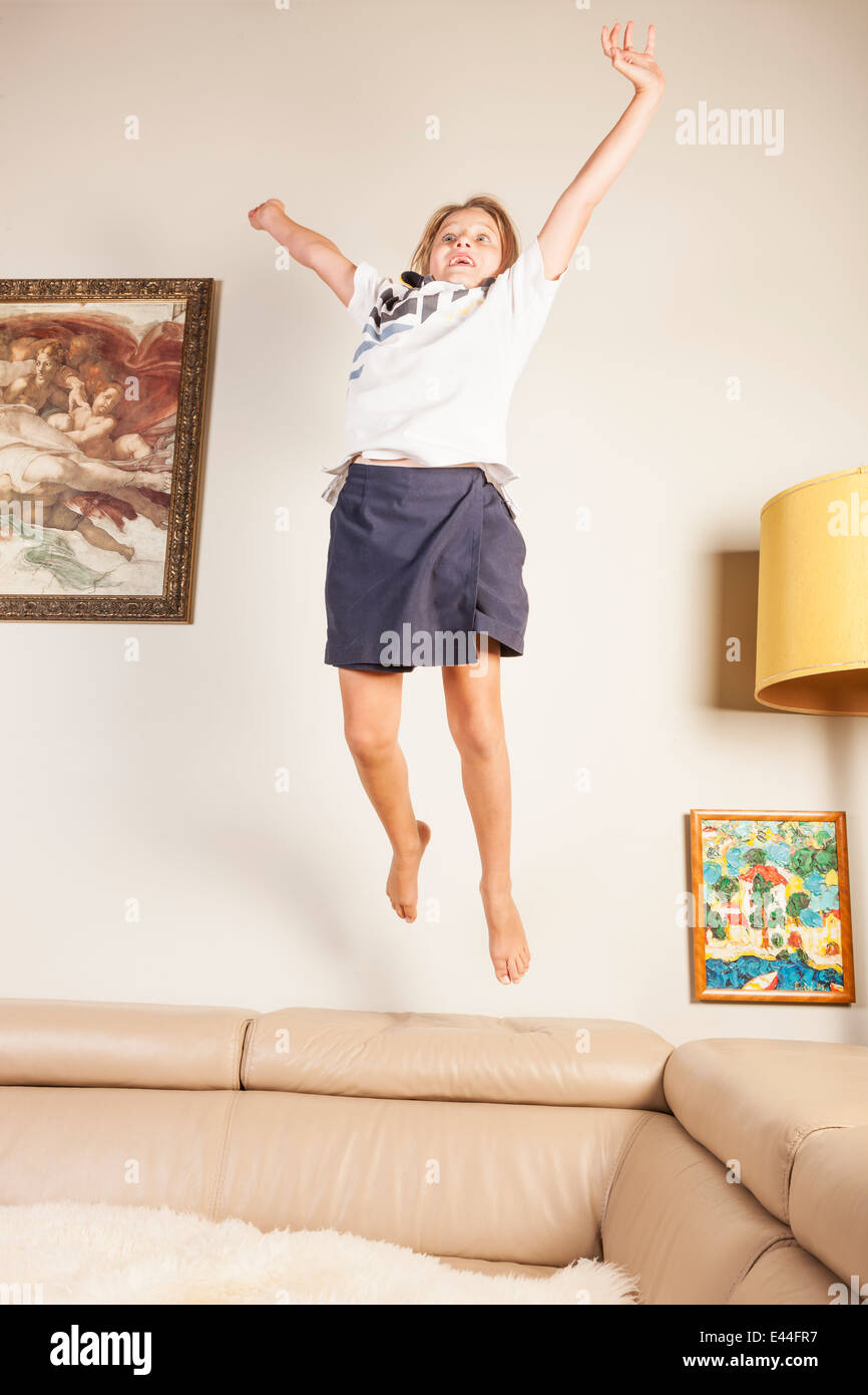 Young girl jumping on sofa at home Stock Photo - Alamy