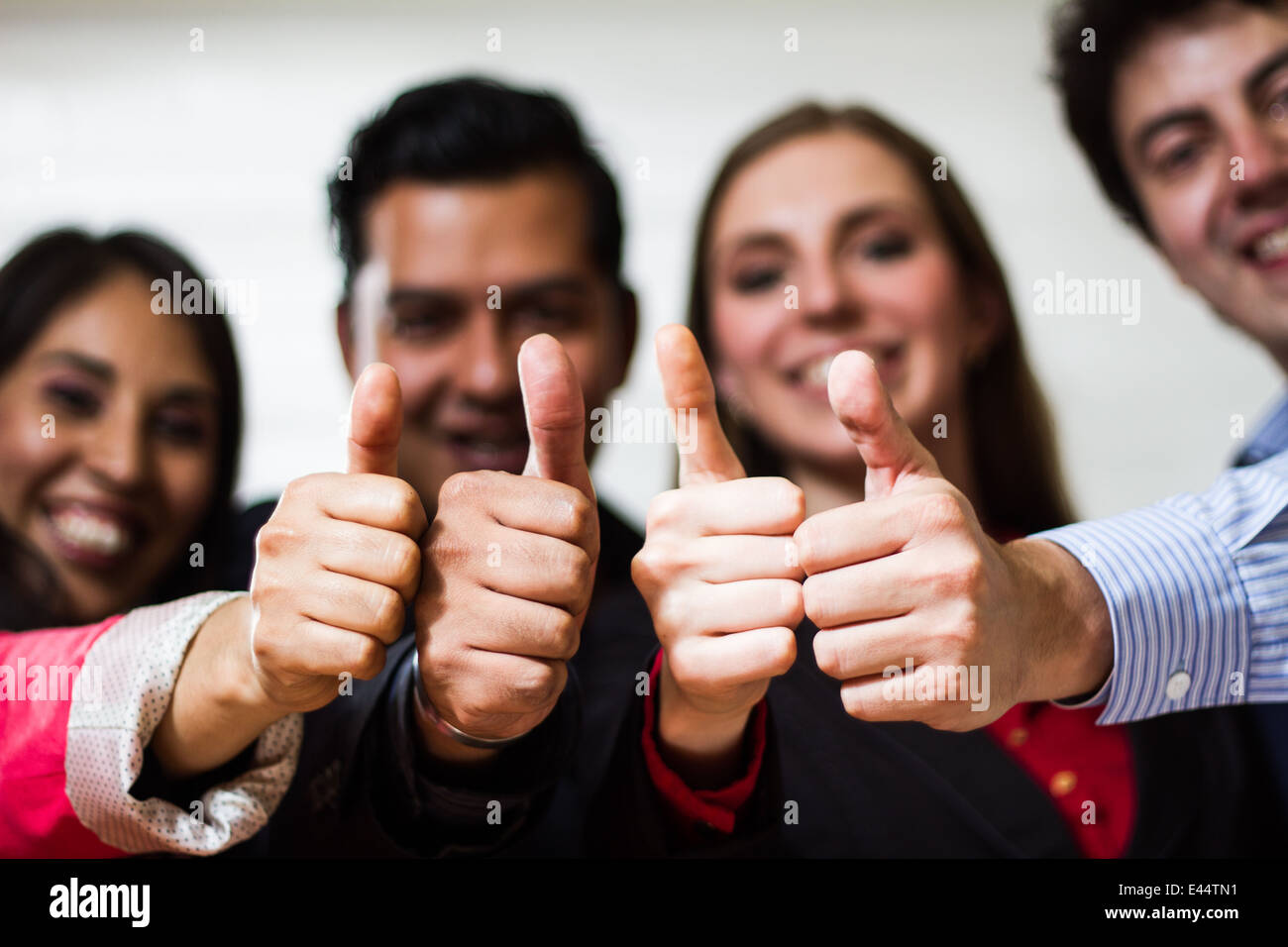 Four people team work, thumbs up Stock Photo - Alamy