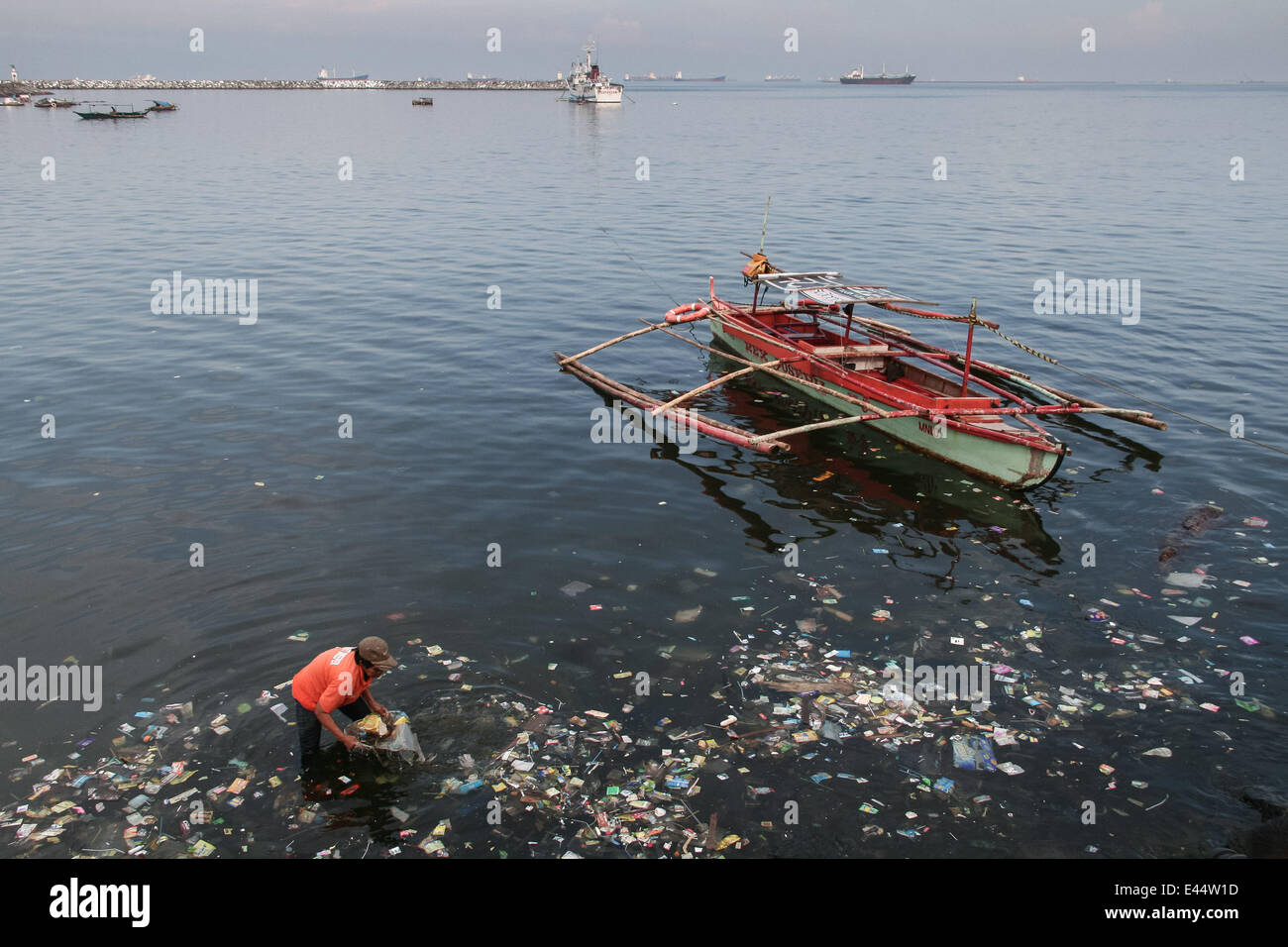 Manila, Philippines. 3rd July, 2014. A volunteer picks up garbage ...