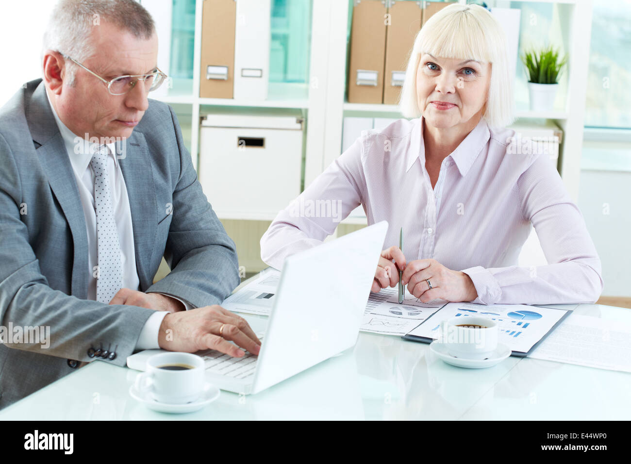 Portrait of pretty secretary looking at camera at workplace with her ...