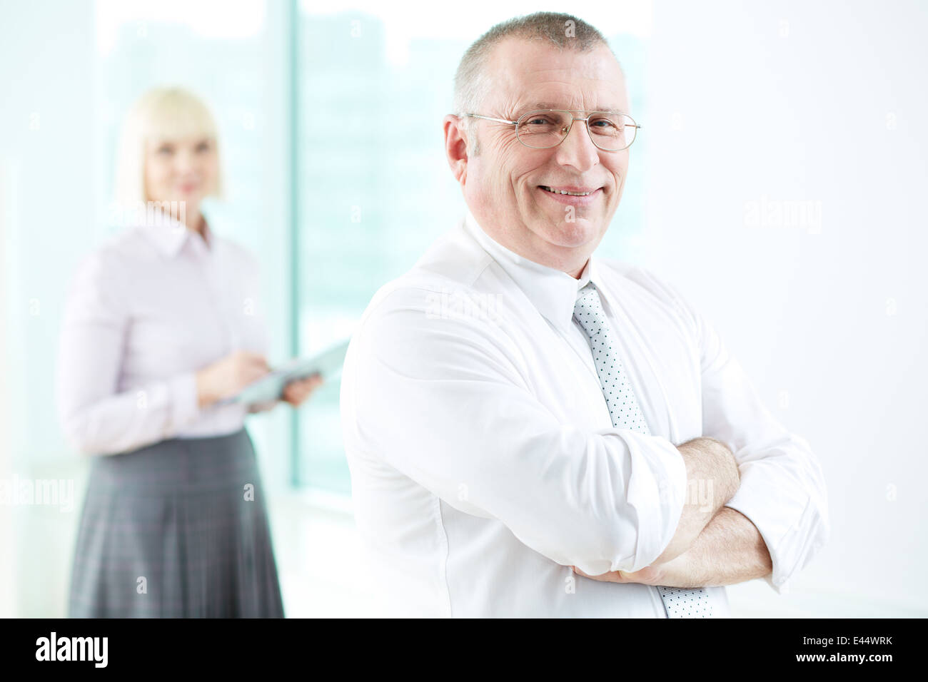 Portrait of smiling boss looking at camera with female standing on ...