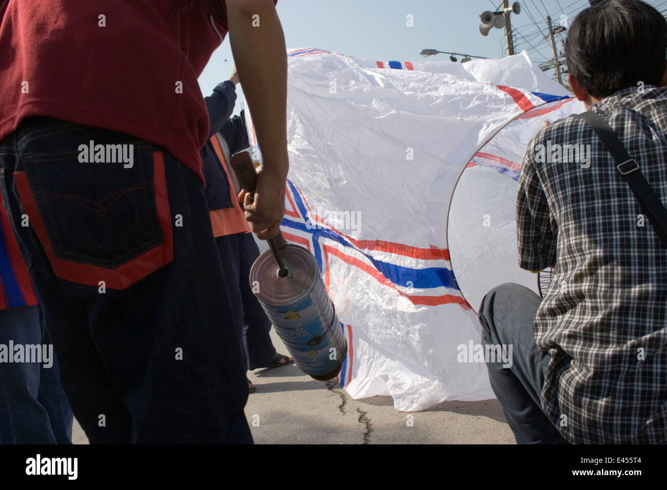 A group of men are using a fan while launching a hot air balloon during ...