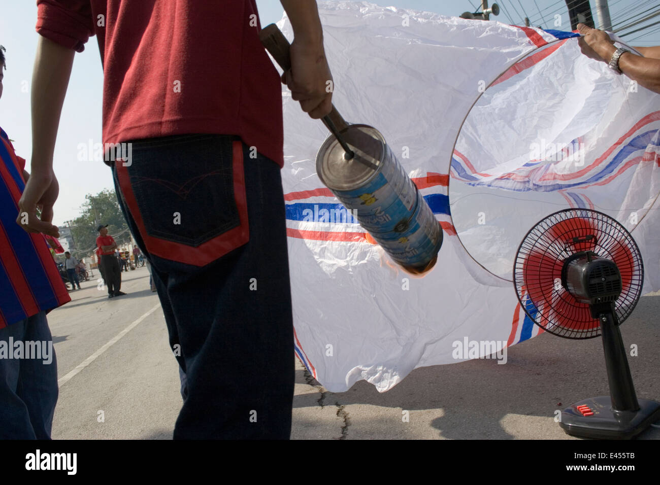 A group of men are using a fan while launching a hot air balloon during ...