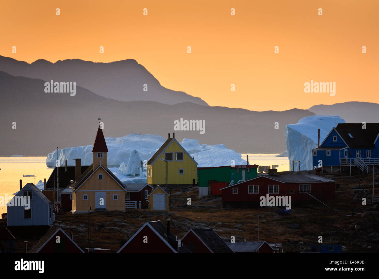 Houses and church in Saqqaq with icebergs on the sea, at sunrise, Disko ...