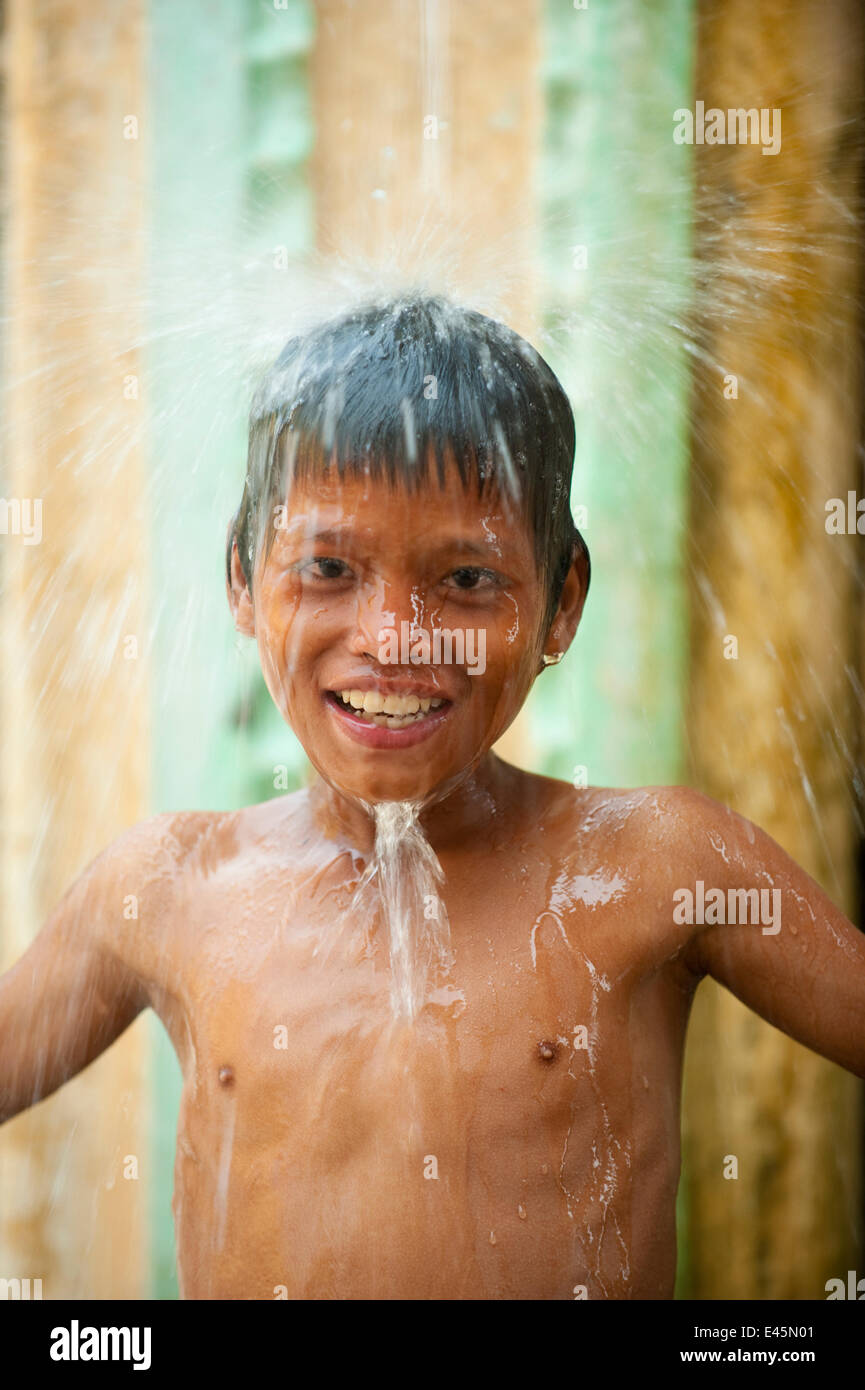 Boy playing in heavy monsoon rain, during the raining season, Bago ...