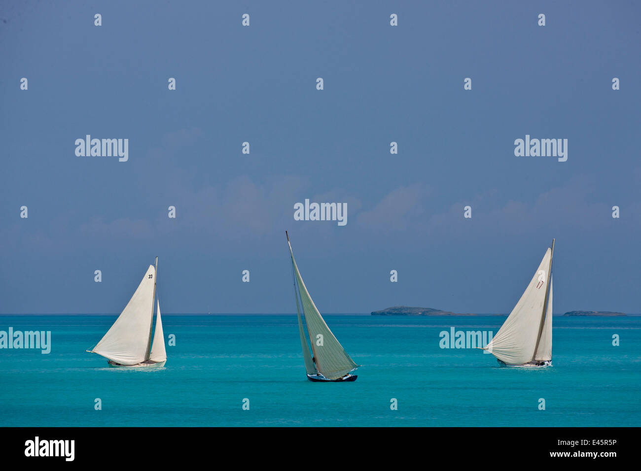 Three boats sailing on turquoise seas during the Bahamian Sloop regatta ...
