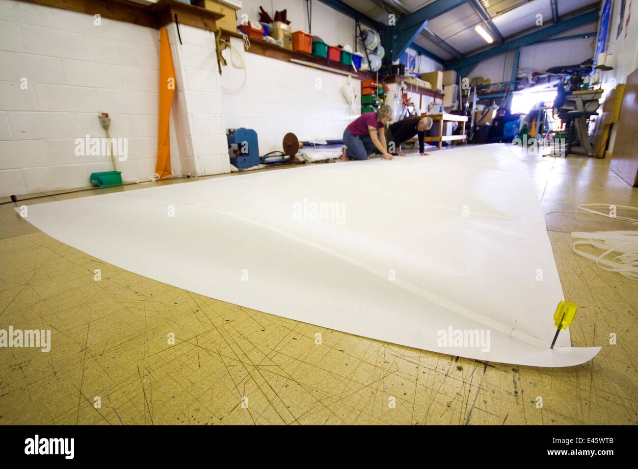 Sailmakers taping cut sections of a mainsail together before stitching ...