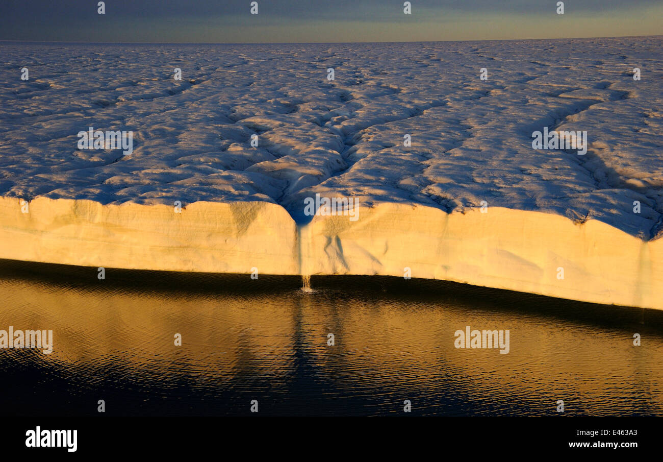 Waterfall from ice cliffs with ice-cap stretching into the distance ...