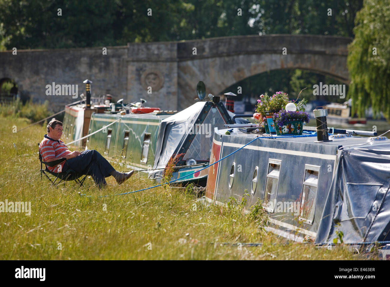 Man relaxing on chair next to his barge, River Thames at Lechlade ...