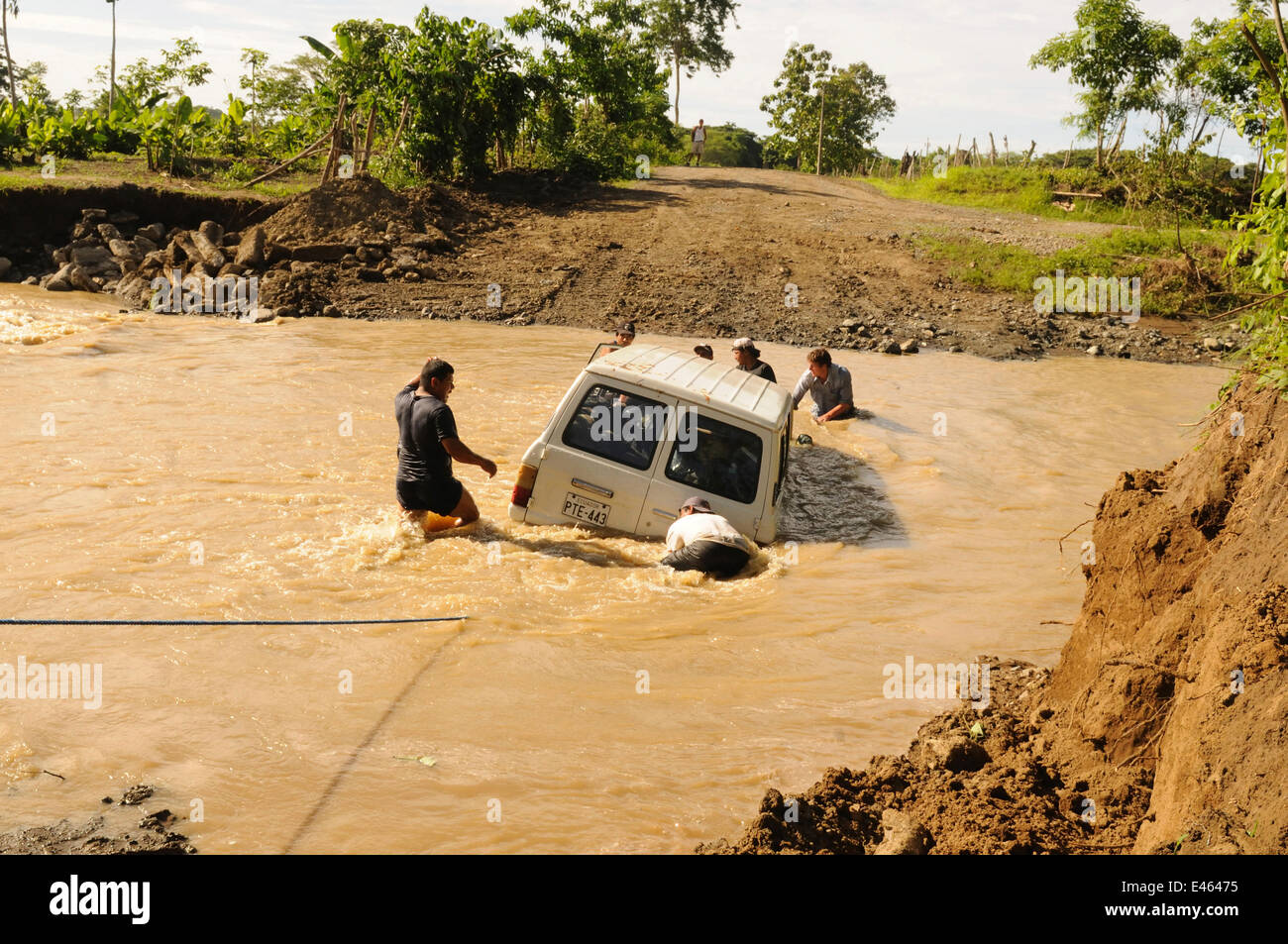 Group of men attempting to rescue a vehicle stuck in flood water, River ...