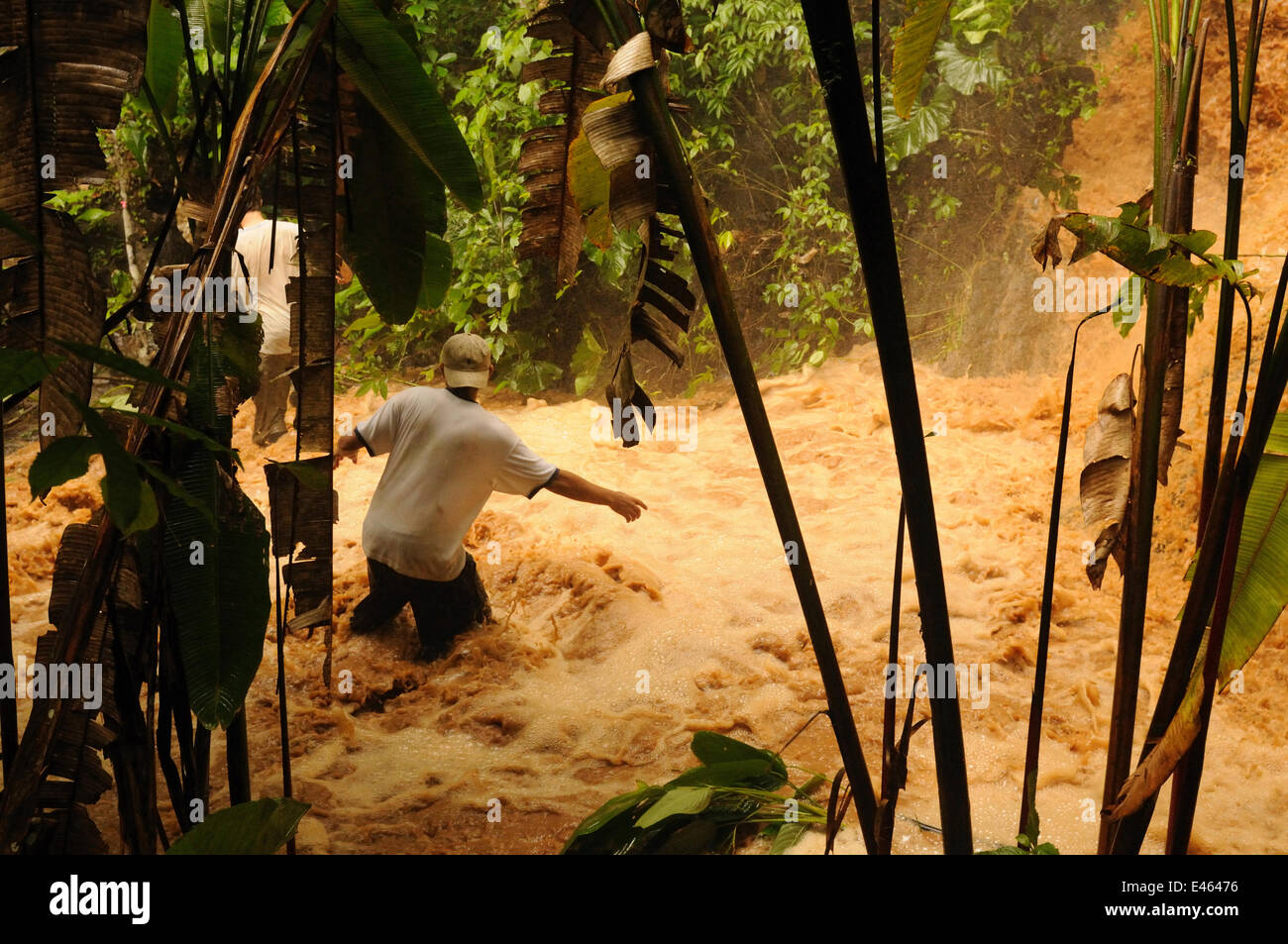 Two men crossing a cloud forest river in spate, Jama Coaque Reserve ...