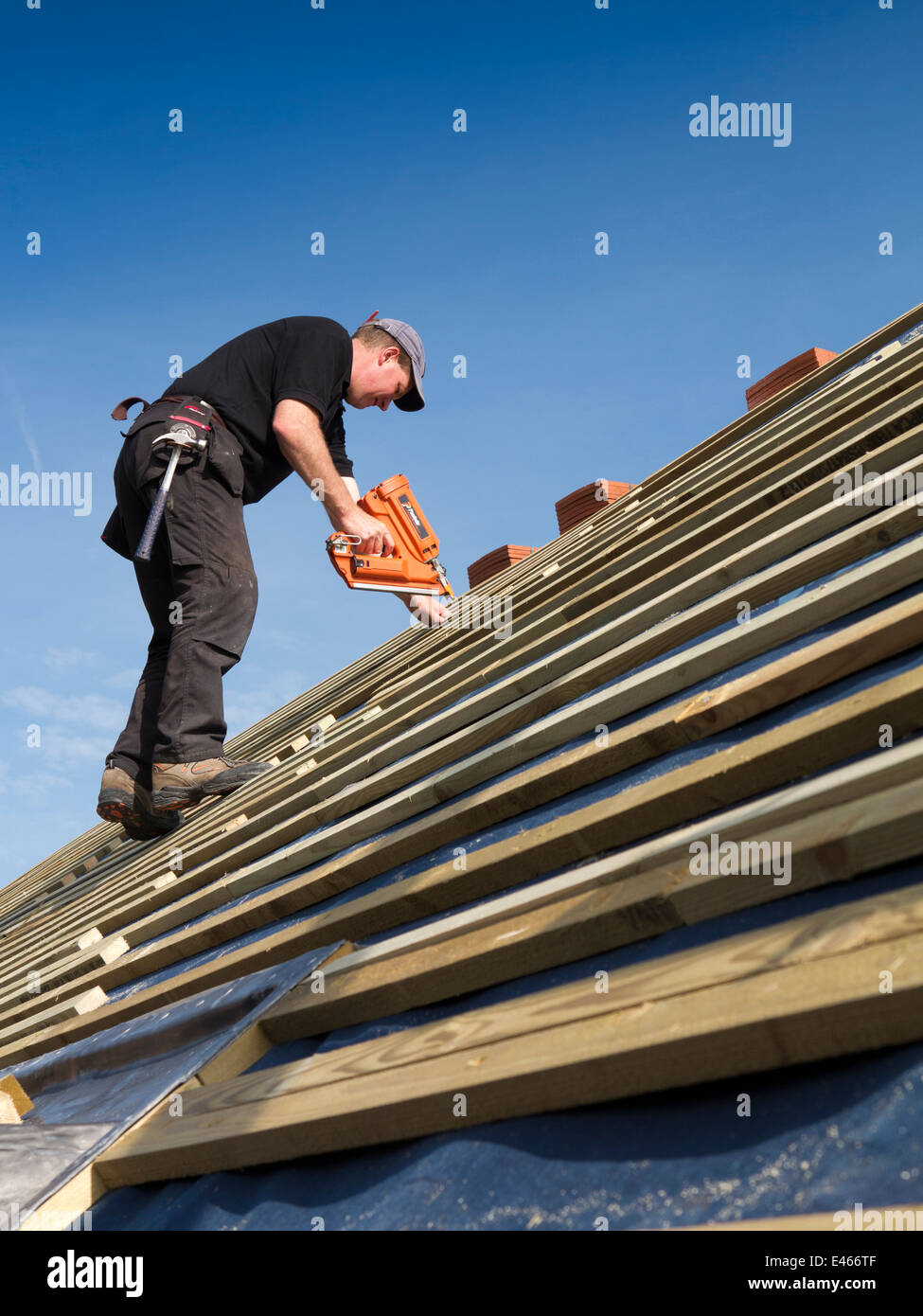 self building house, constructing roof, man fixing roofing laths with ...