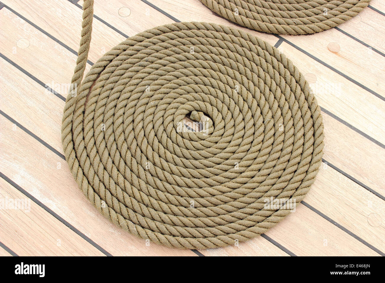 Old nautical thick rope wrapped in spiral lying on weathered deck of ...