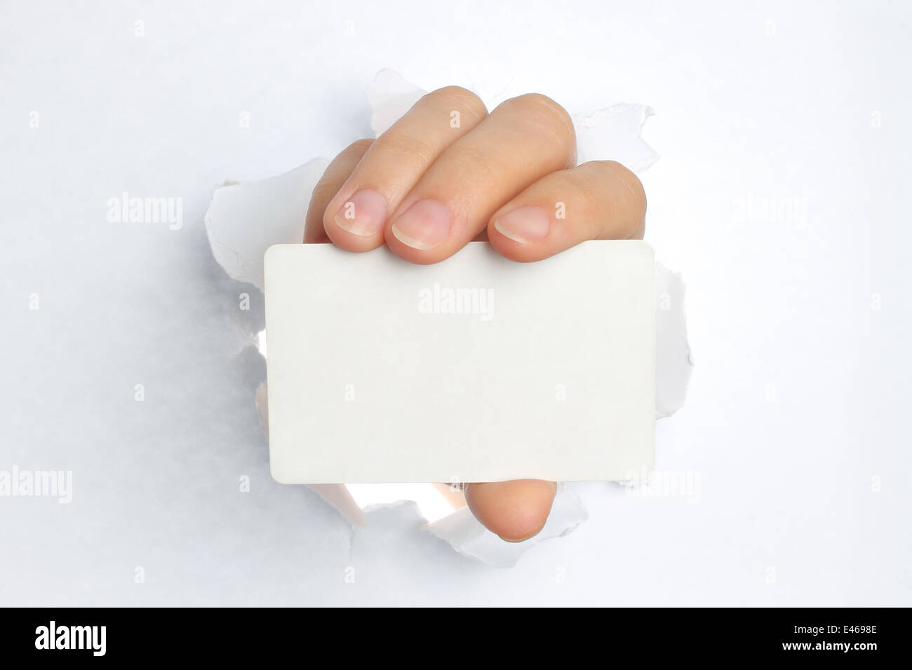 Hand holds white card through white torn paper Stock Photo - Alamy