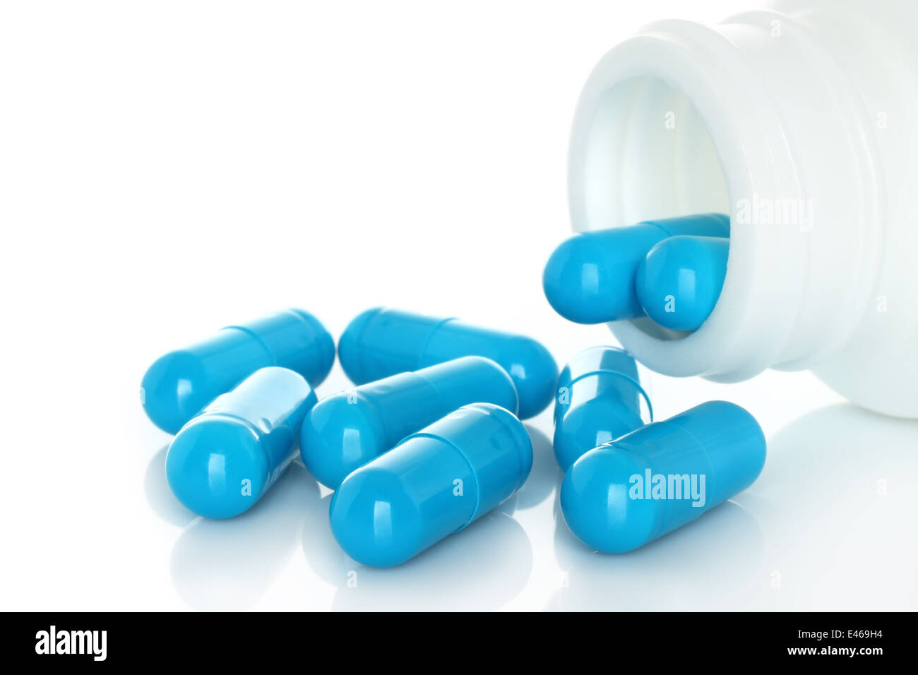 Pills pouring from white bottle on white background Stock Photo - Alamy