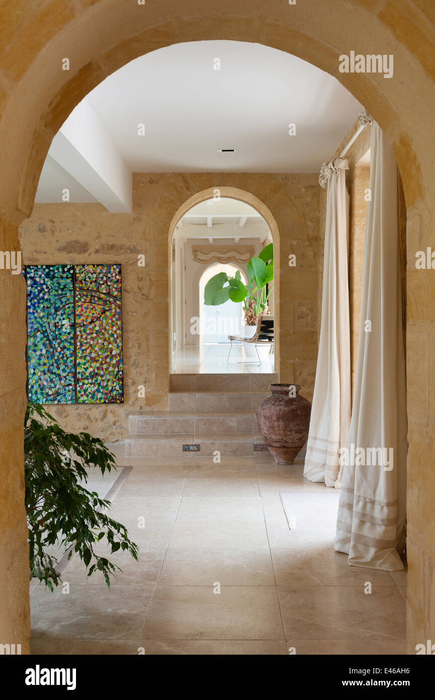 A series of arches leading through a stone walled house. The floor is ...