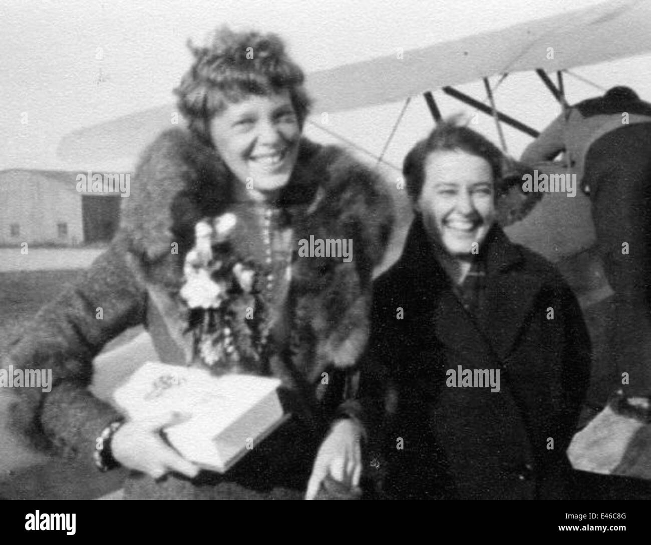 This photograph depicts Amelia Earhart standing next to her airplane ...