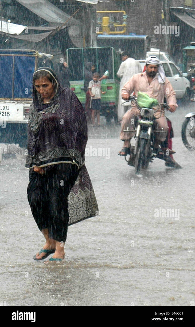 Lahore, Pakistan. 3rd July, 2014. A woman walks in a flooded street ...