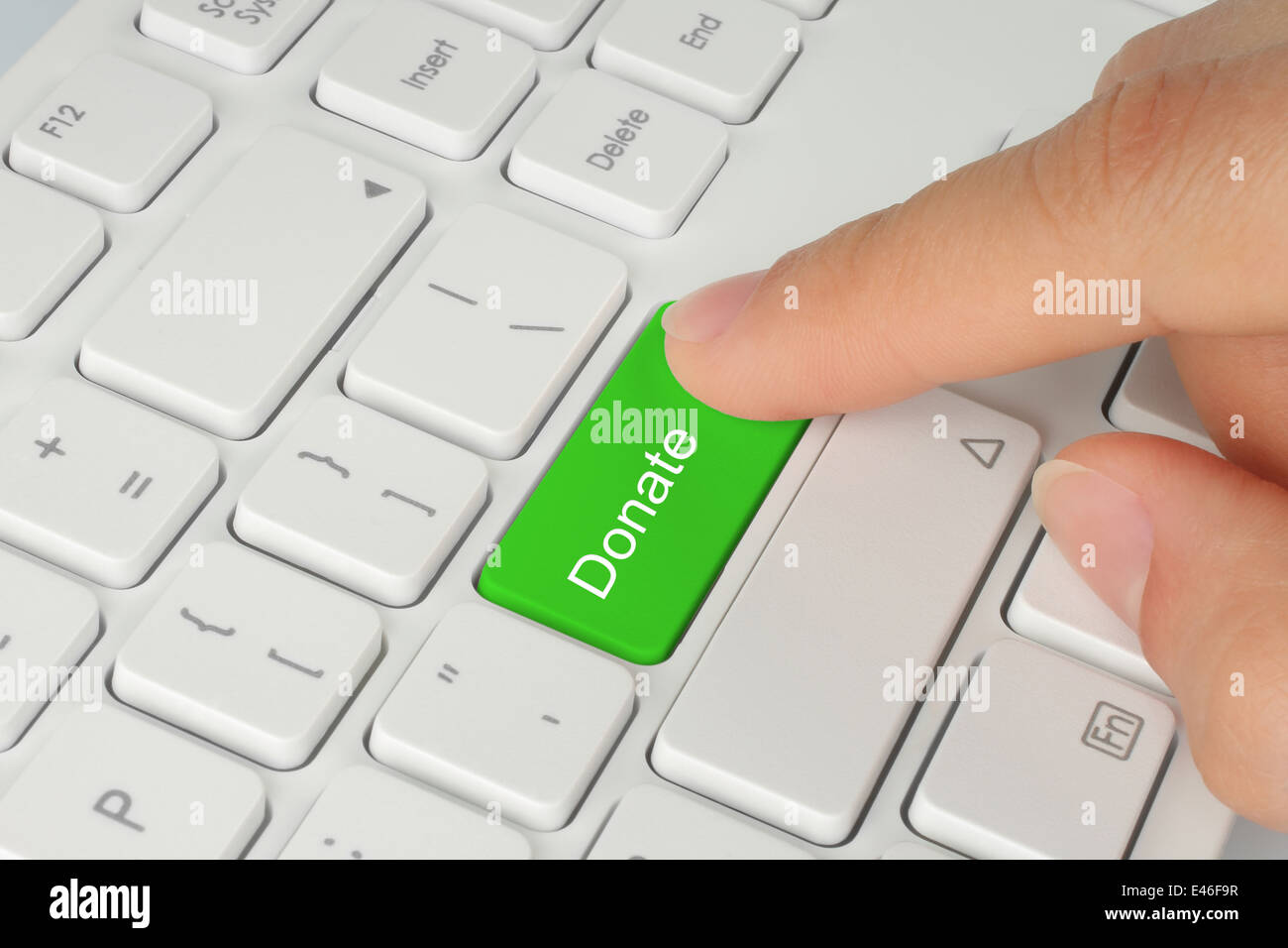 Hand pushing green donate button on white keyboard Stock Photo - Alamy
