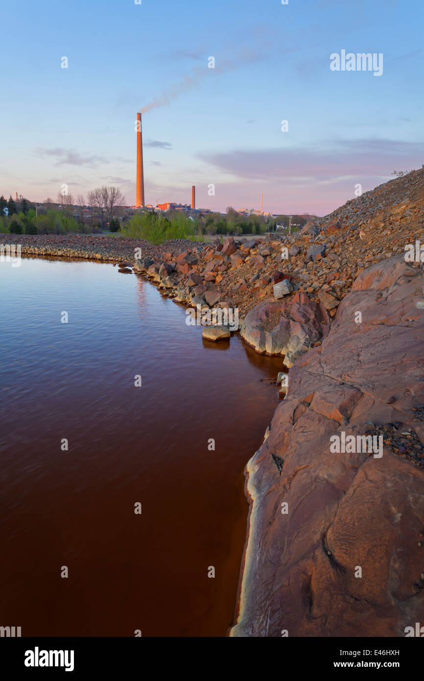 Heavy rust colored sediment at the bottom of a tailings pond turning it ...