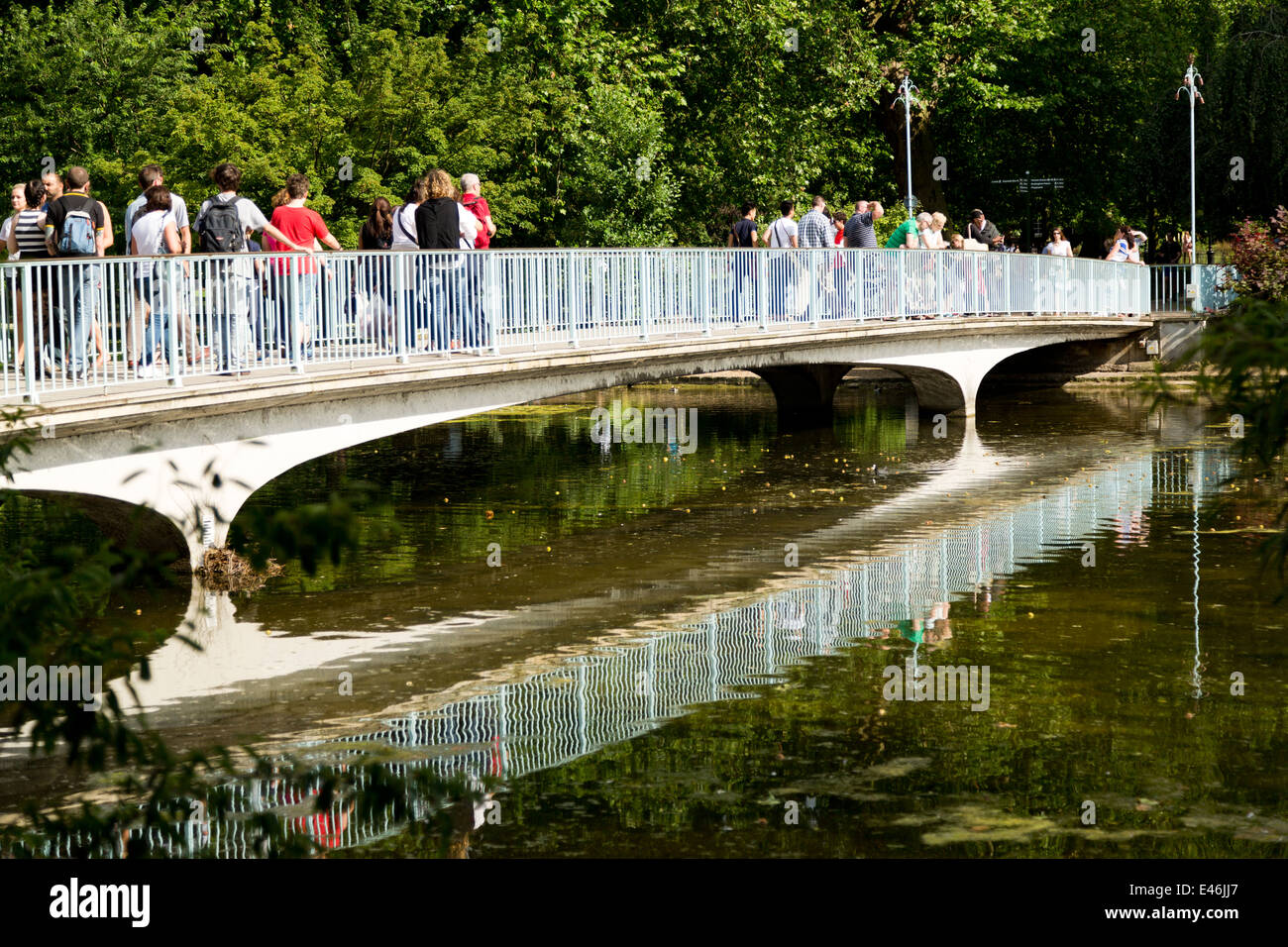 People walking along the blue bridge on St. James's Park lake, London ...