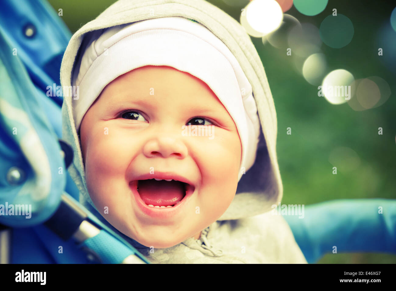 Little baby girl laughs in pram on the walk. Toned effect Stock Photo ...