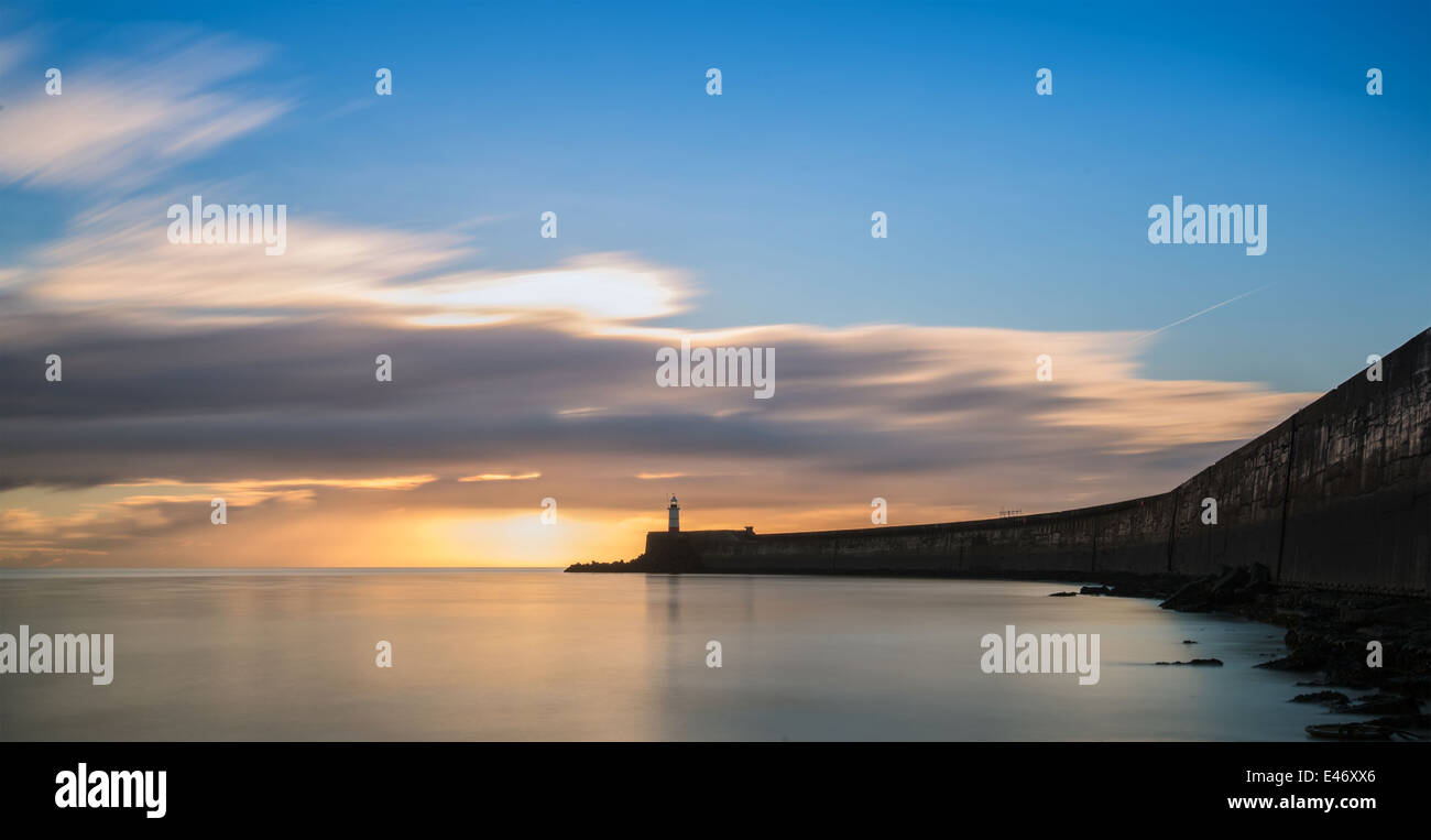 Stunning sunrise over ocean with lighthouse and harbor wall Stock Photo ...
