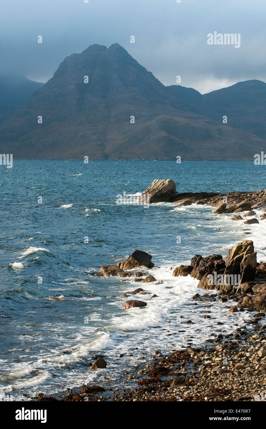 Portrait view across the sea to the Island of Soay from the rocky shore ...
