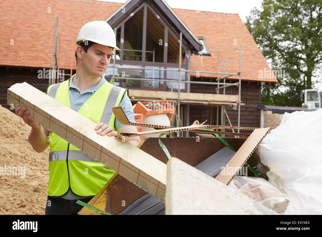 Builder Throwing Waste Into Skip On Construction Site Stock Photo - Alamy