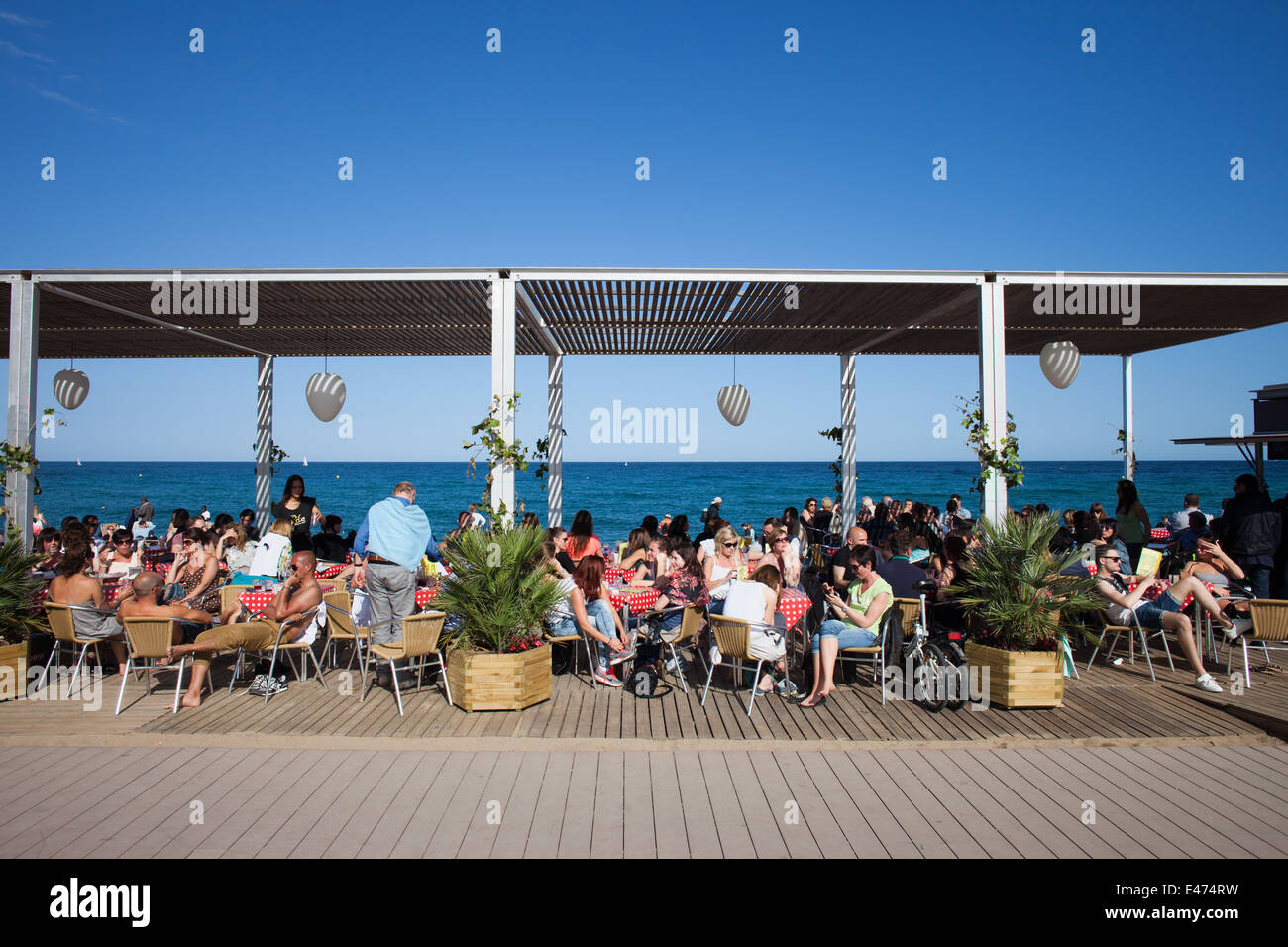 People chill out in seaside cafe at the beach and Barceloneta promenade ...