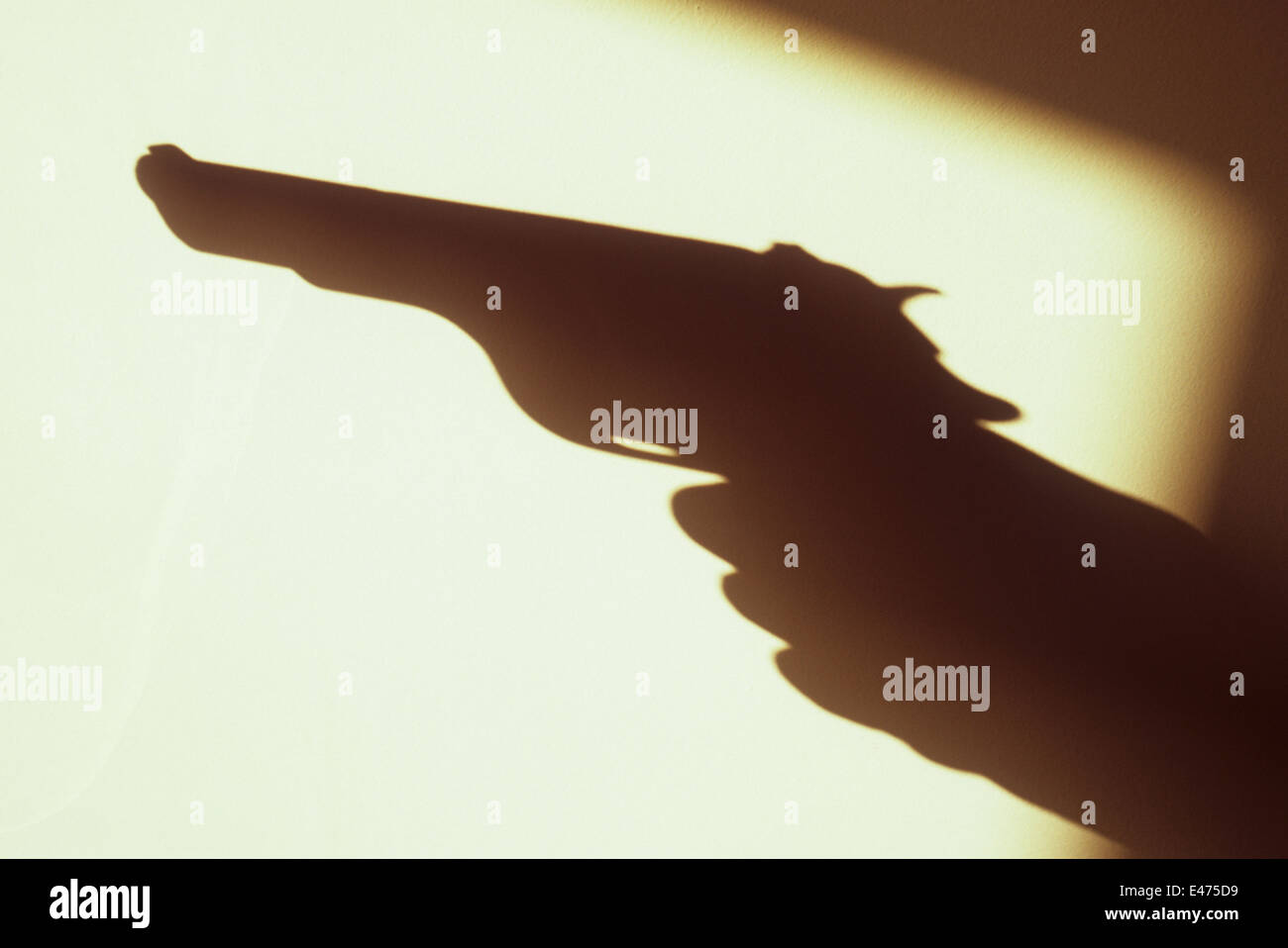 Shadow of hand holding gun or pistol framed in warm light of shadow ...