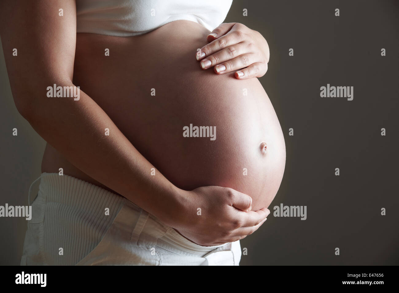 Low Key Image Of Pregnant Woman Holding Belly Stock Photo - Alamy