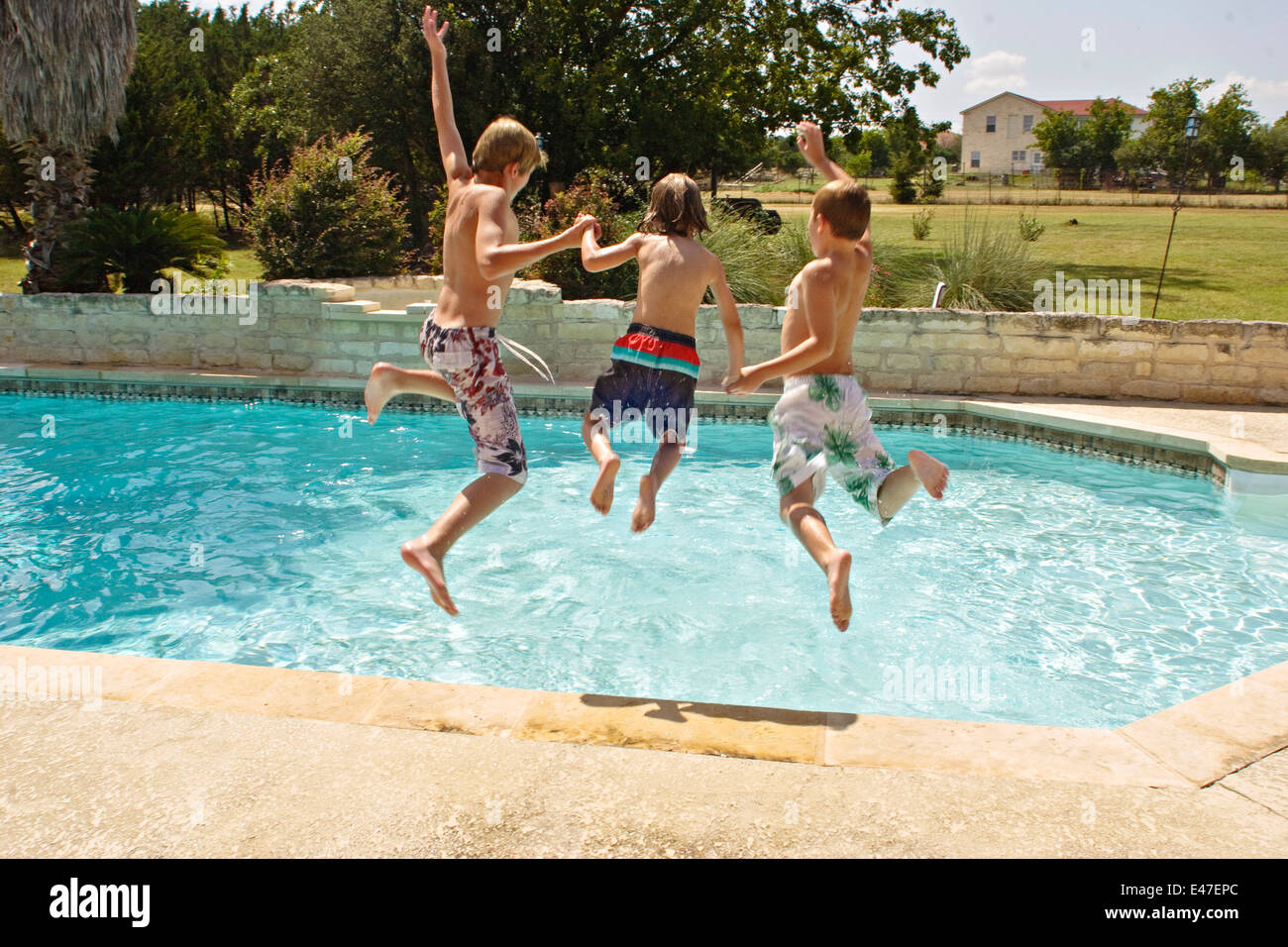 Kids swimming - three boys enjoying hot summer by jumping into swimming ...