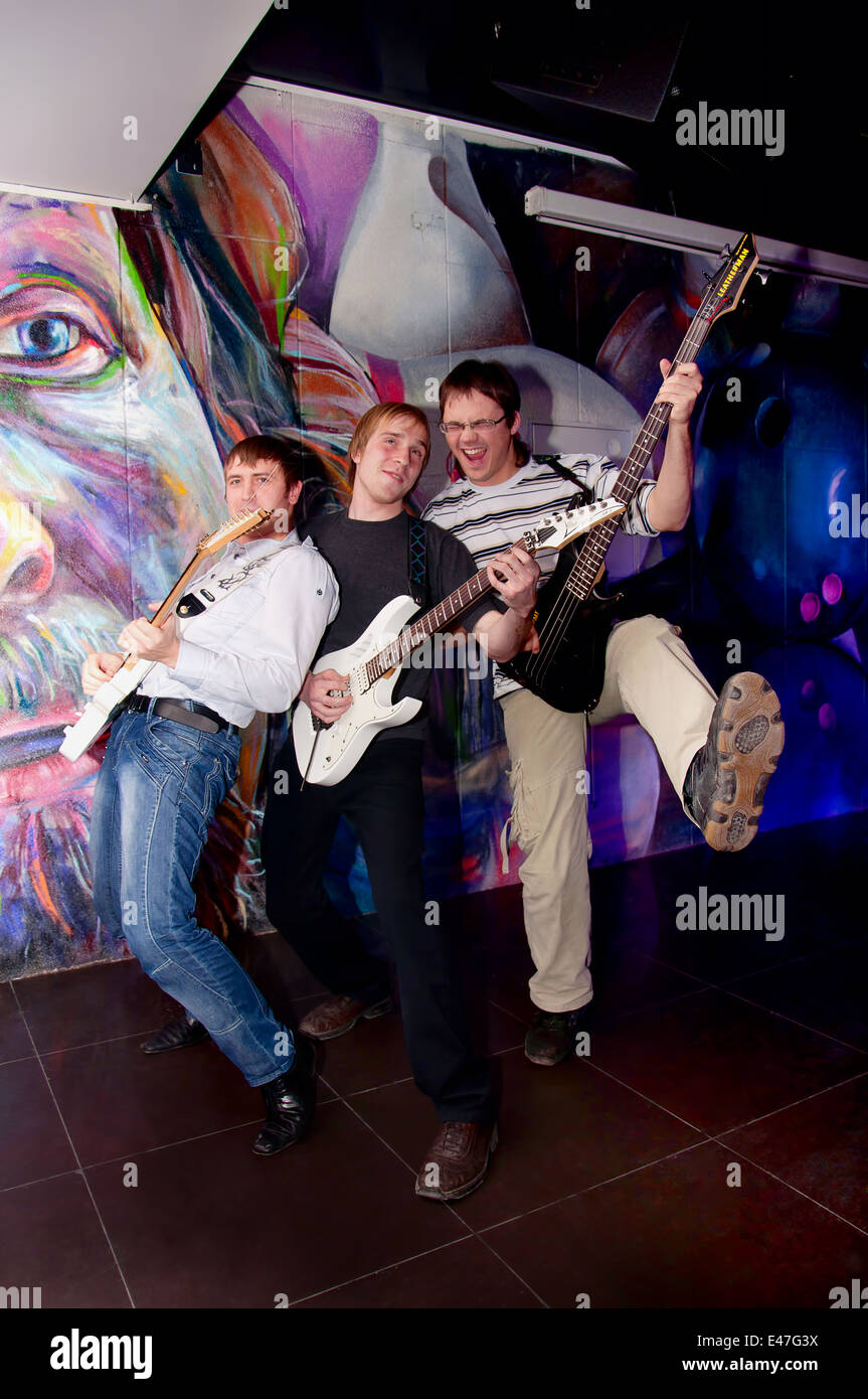 Three rock guitarists are joking, smiling, and playing cheerful rock ...