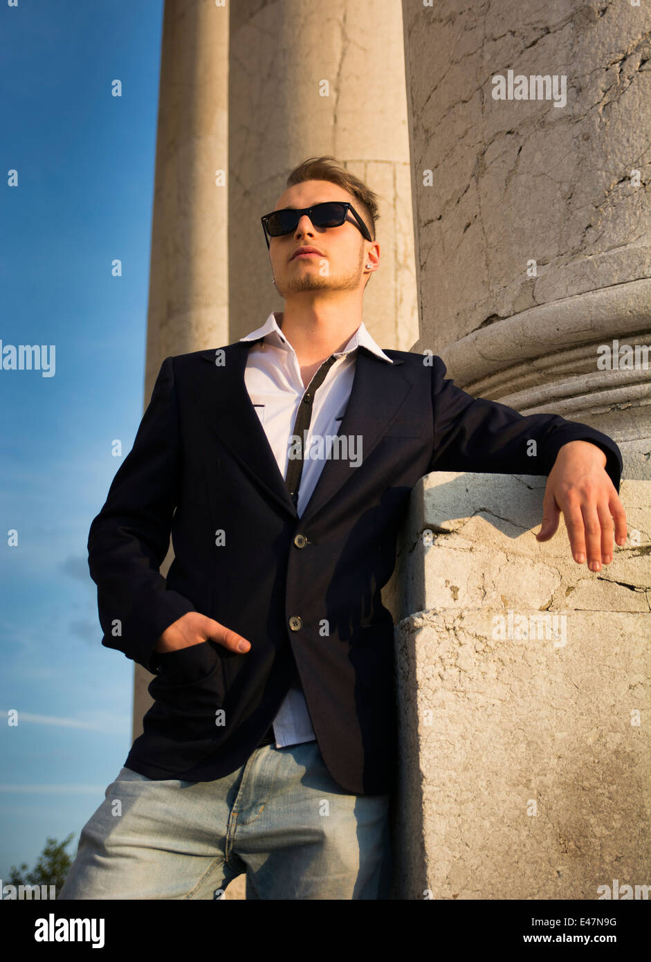 Handsome blond young man with marble columns behind him, looking away ...