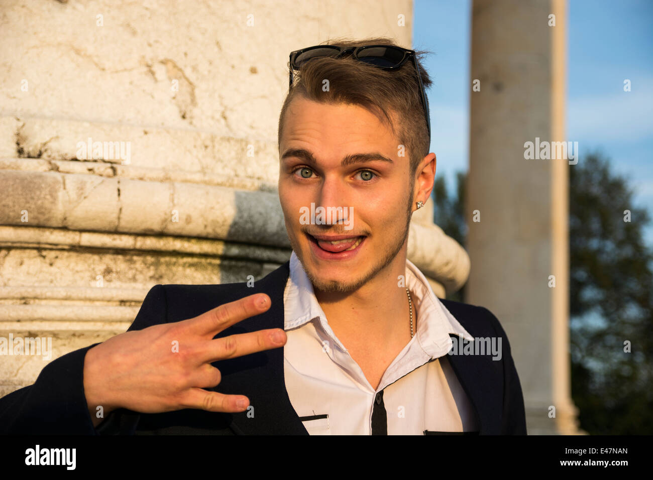 Blond young man with cute, funny expression. Outdoor shot at sundown ...