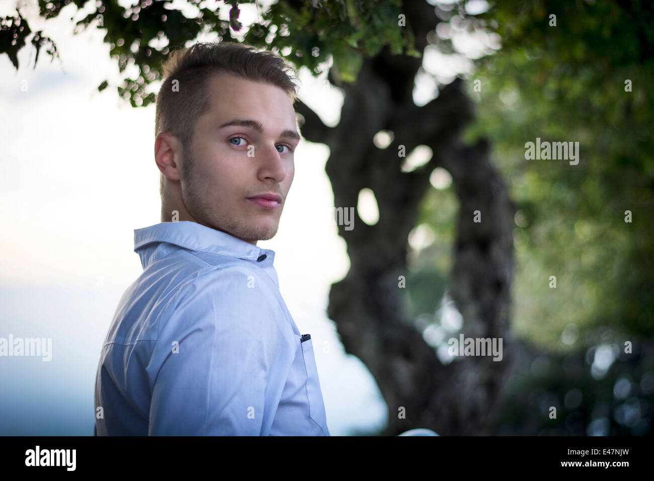 Profile shot of handsome young man outdoors looking at camera Stock ...