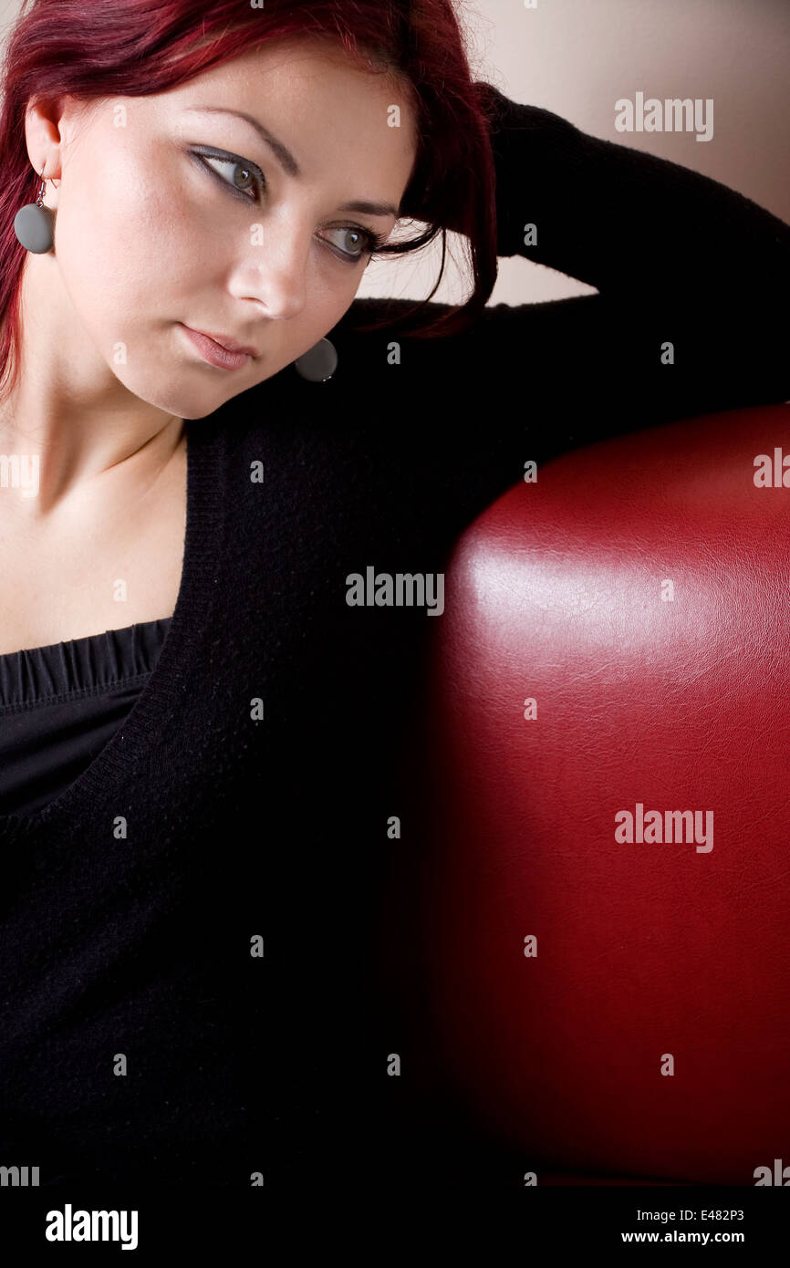 Sad girl relaxing on a red sofa and thinking at something Stock Photo ...