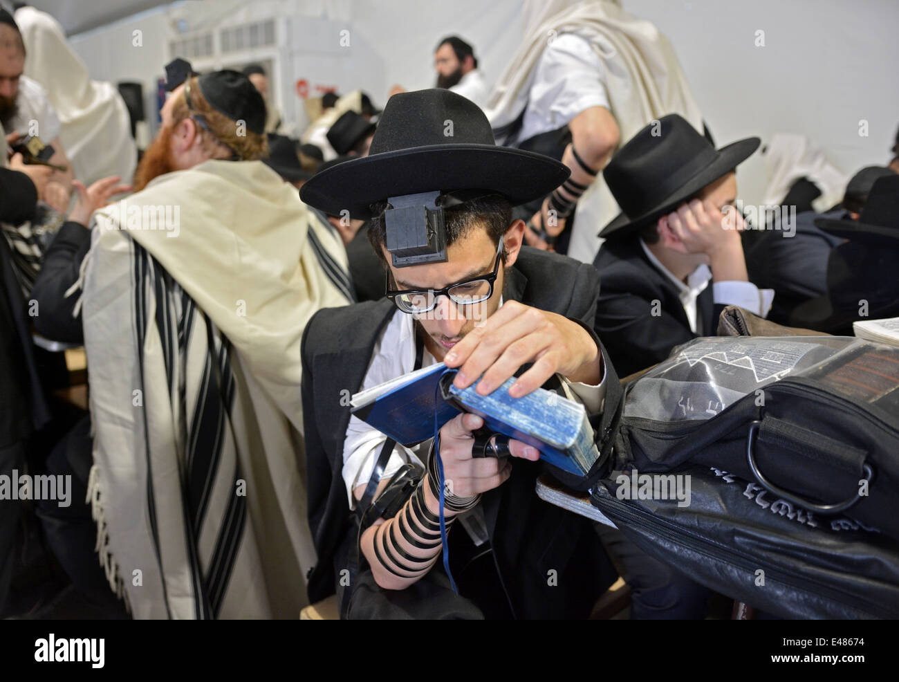 A religious Jewish young man reading at morning prayers at the Ohel in ...